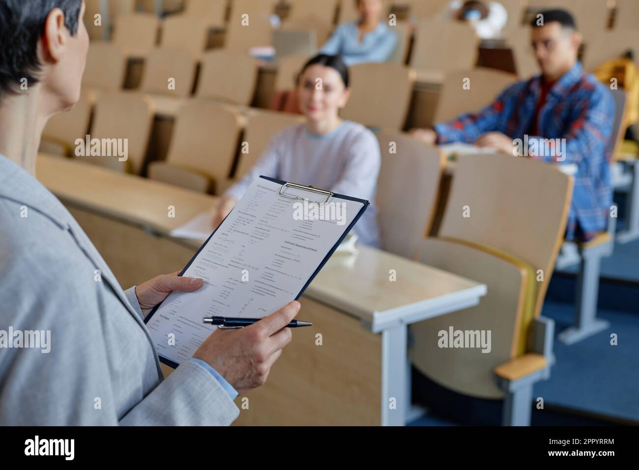 Lecturer with documents reading lecture to students while they sitting ...