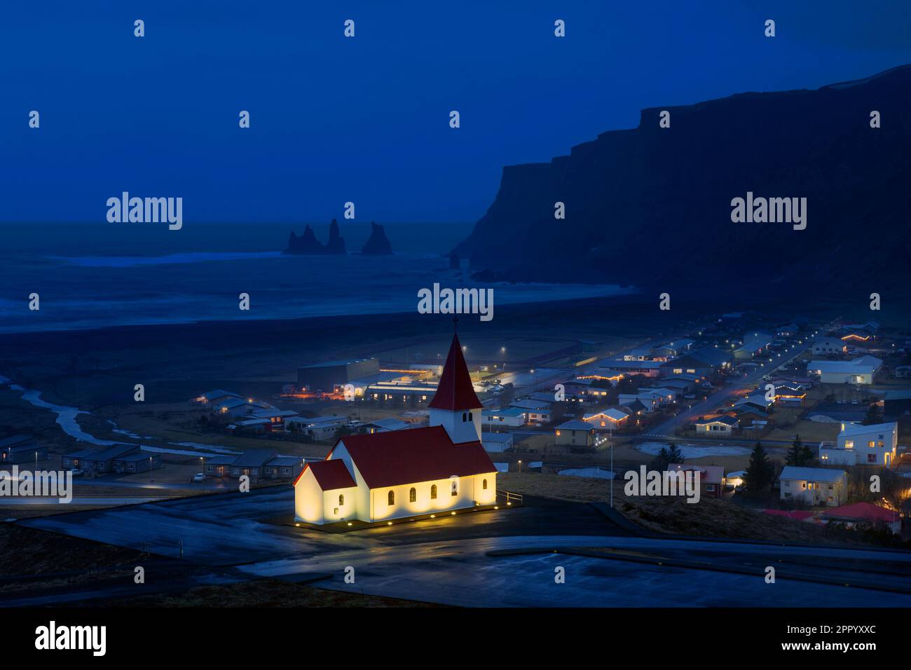 Illuminated Víkurkirkja church at the village Vík í Mýrdal in winter ...