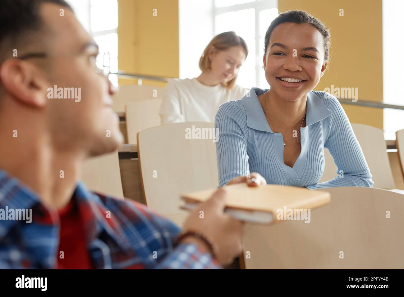 Group of students talking to each other while sitting at desk at ...