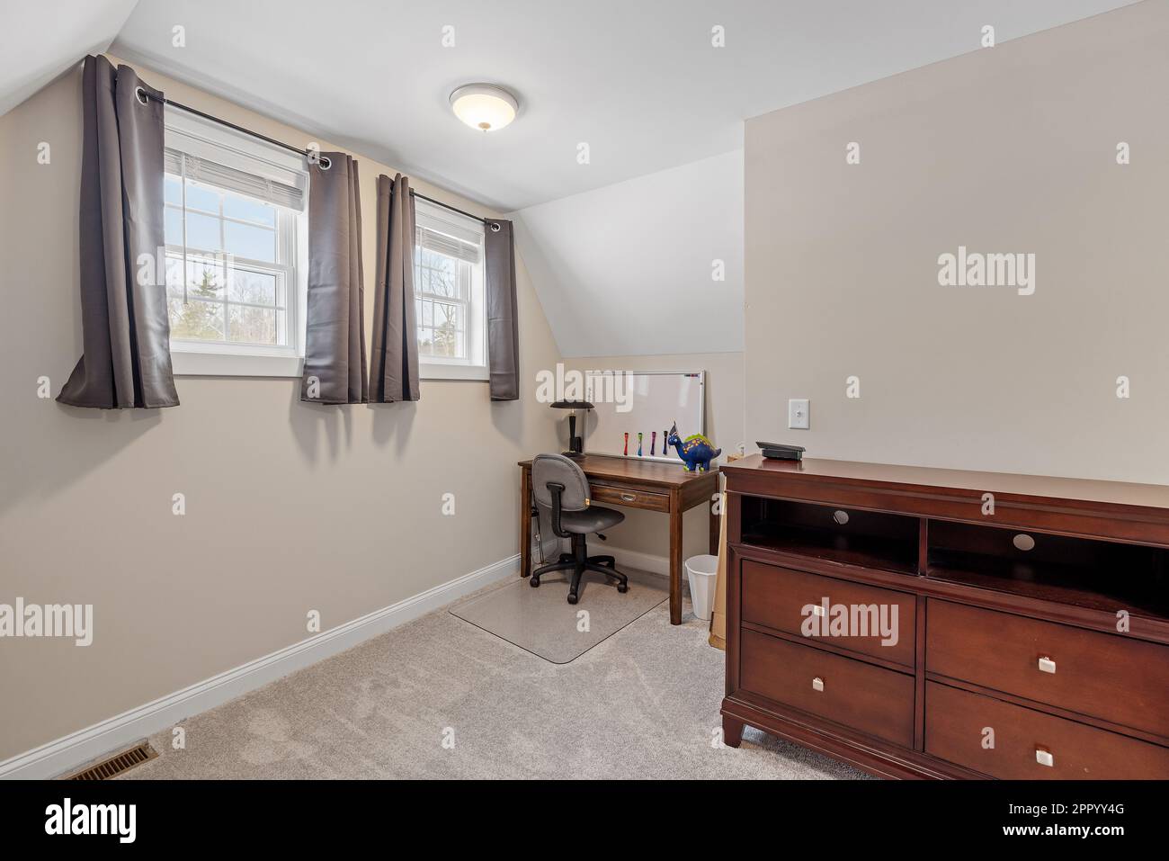 A room with two small windows, a wooden desk and a dresser Stock Photo ...