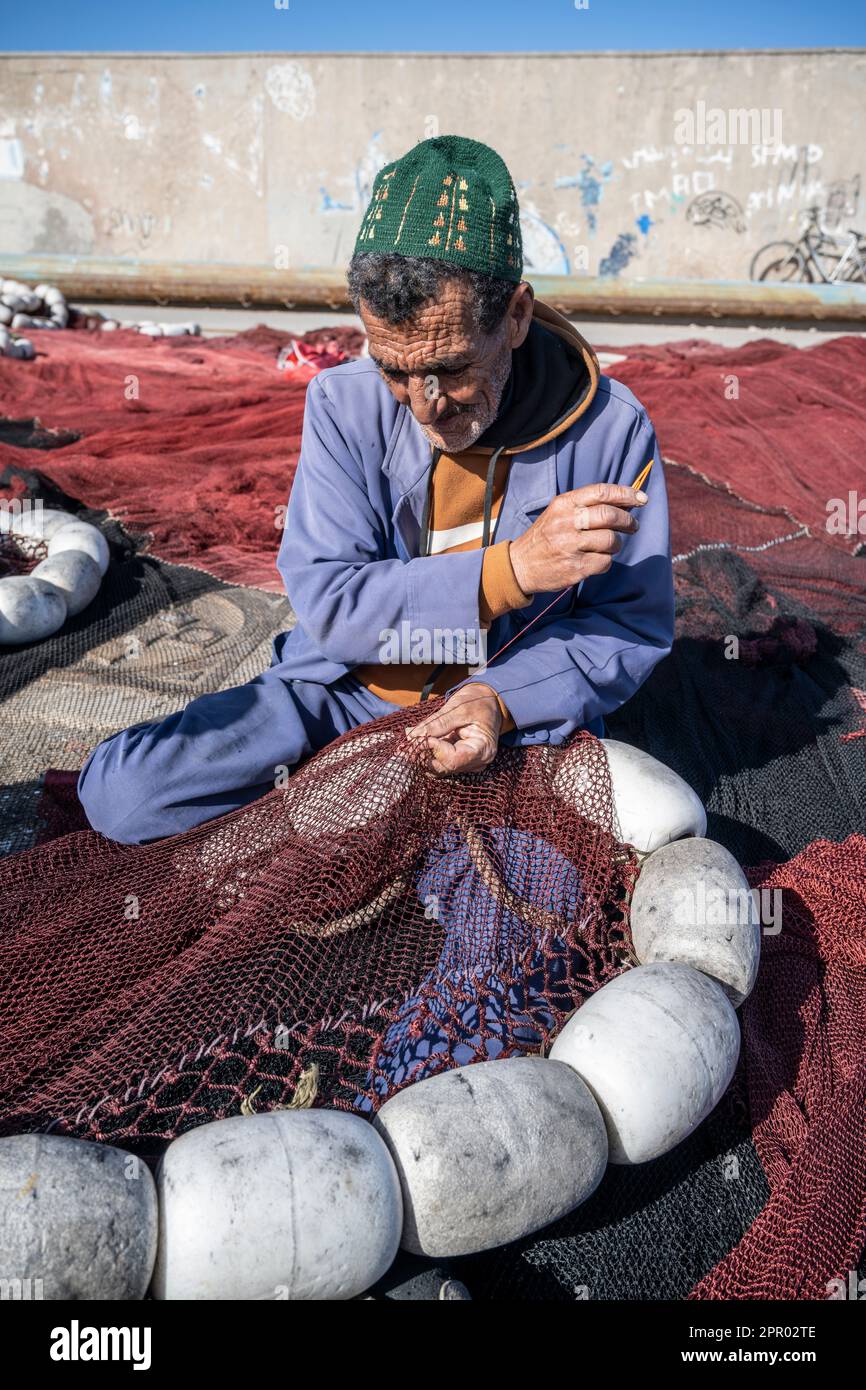 Fisherman repairing fishing nets in the port of Essaouira Stock Photo ...