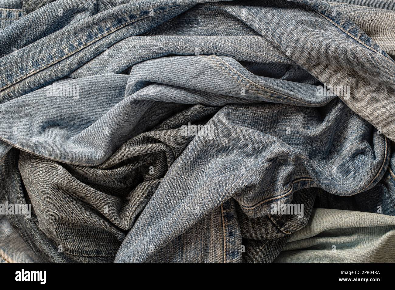Lots of crumpled jeans pants, close up. Denim background. The concept ...