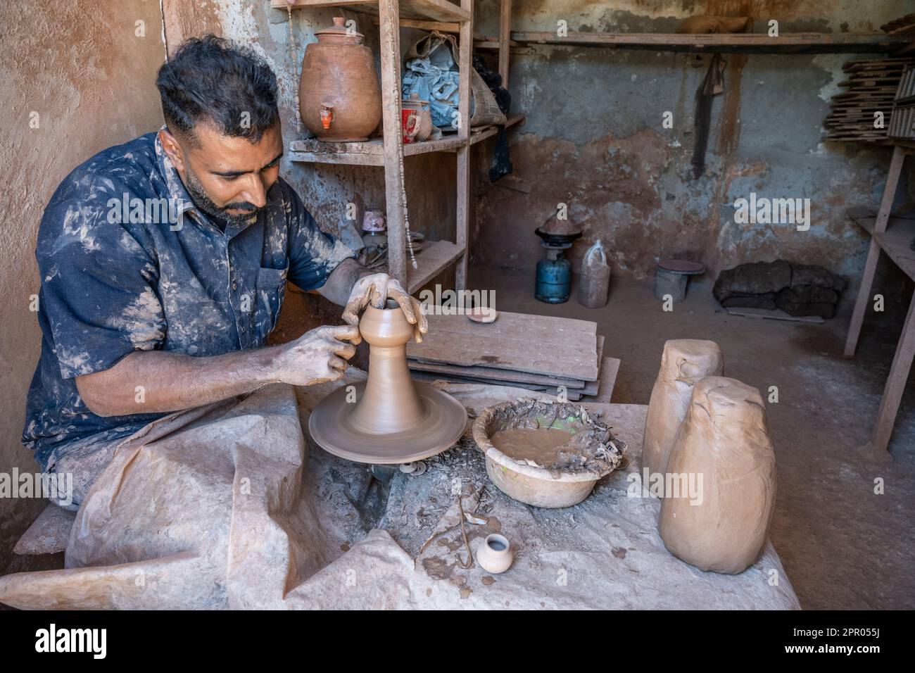 Craftsman manufacturing a ceramic vessel on a bench with a potter's ...