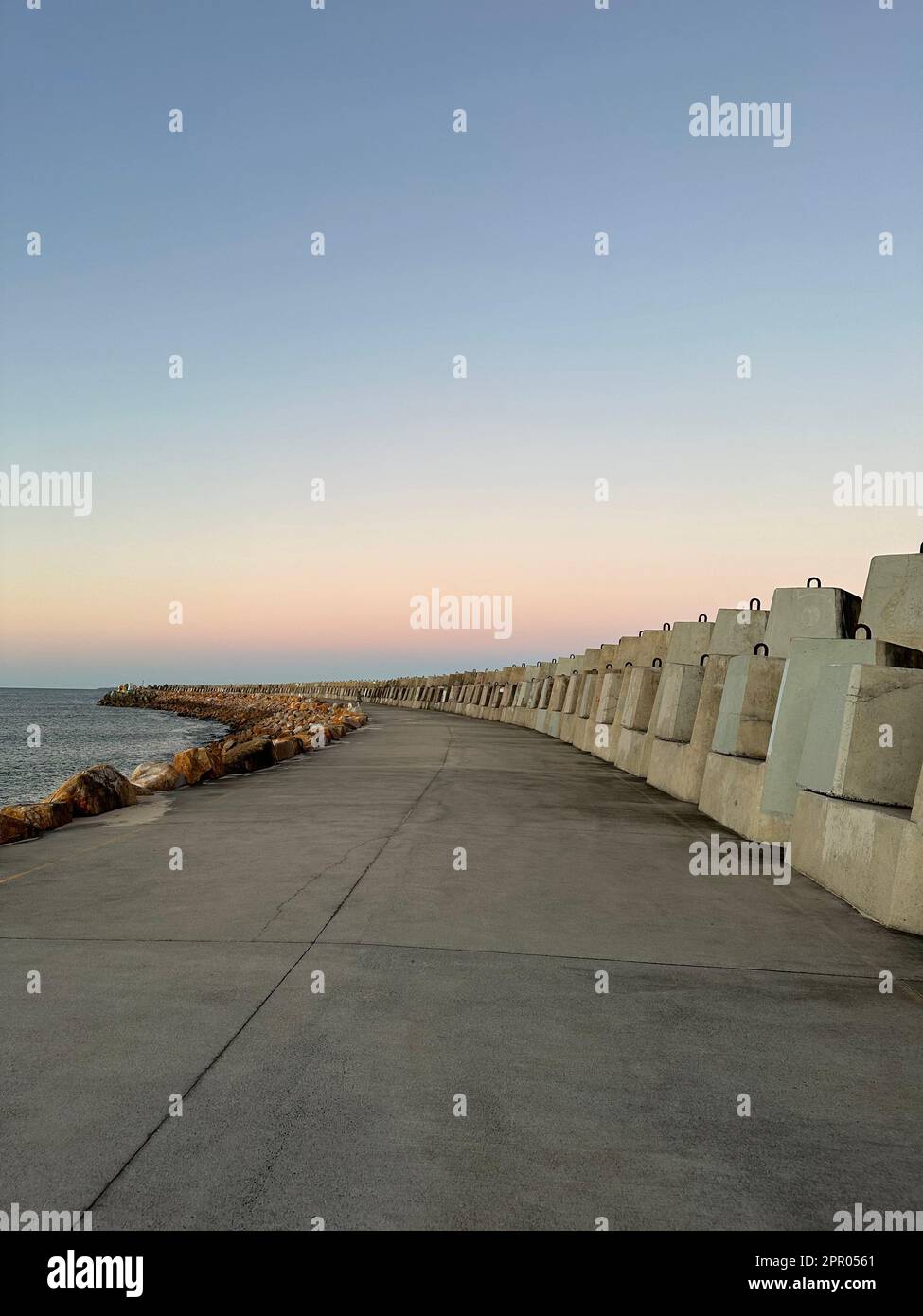 A scenic pathway made of concrete with benches facing the ocean at ...