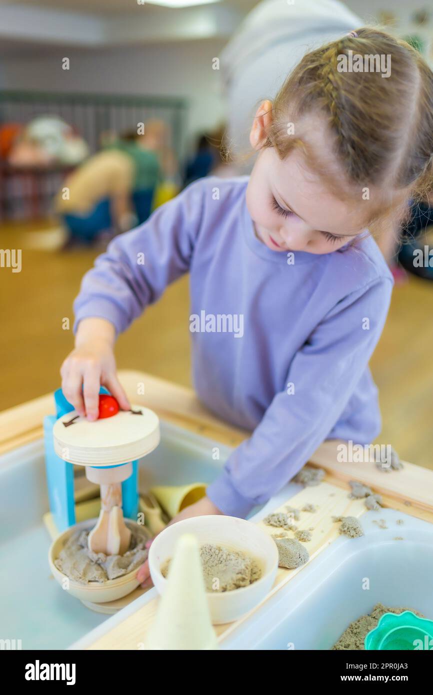Little girl playing with kinetic sand and wooden toys. Sensory ...