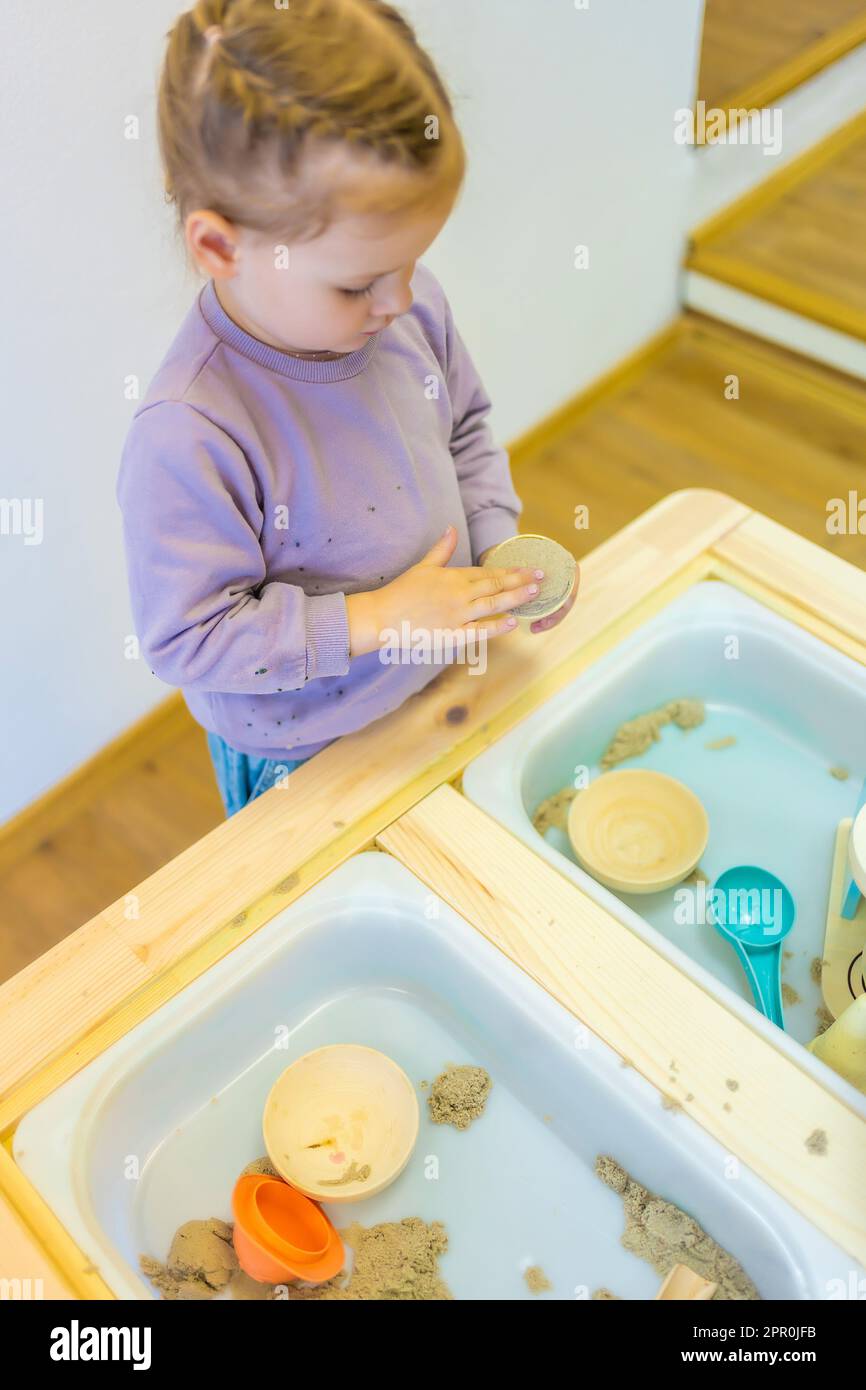 Little girl playing with kinetic sand and wooden toys. Sensory ...