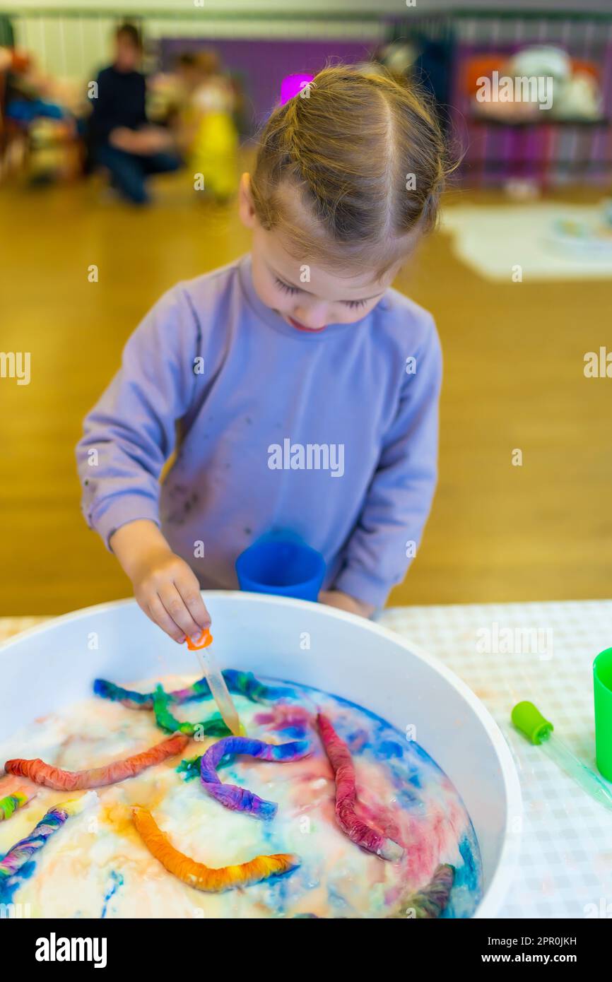 Little girl dripping water on colorful paper worms. Sensory development ...