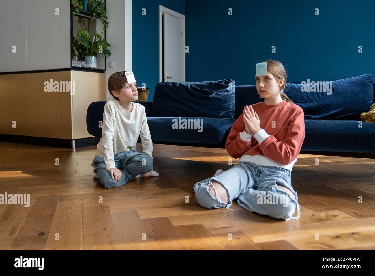 Small children boy and girl playing guessing game with sticky notes ...