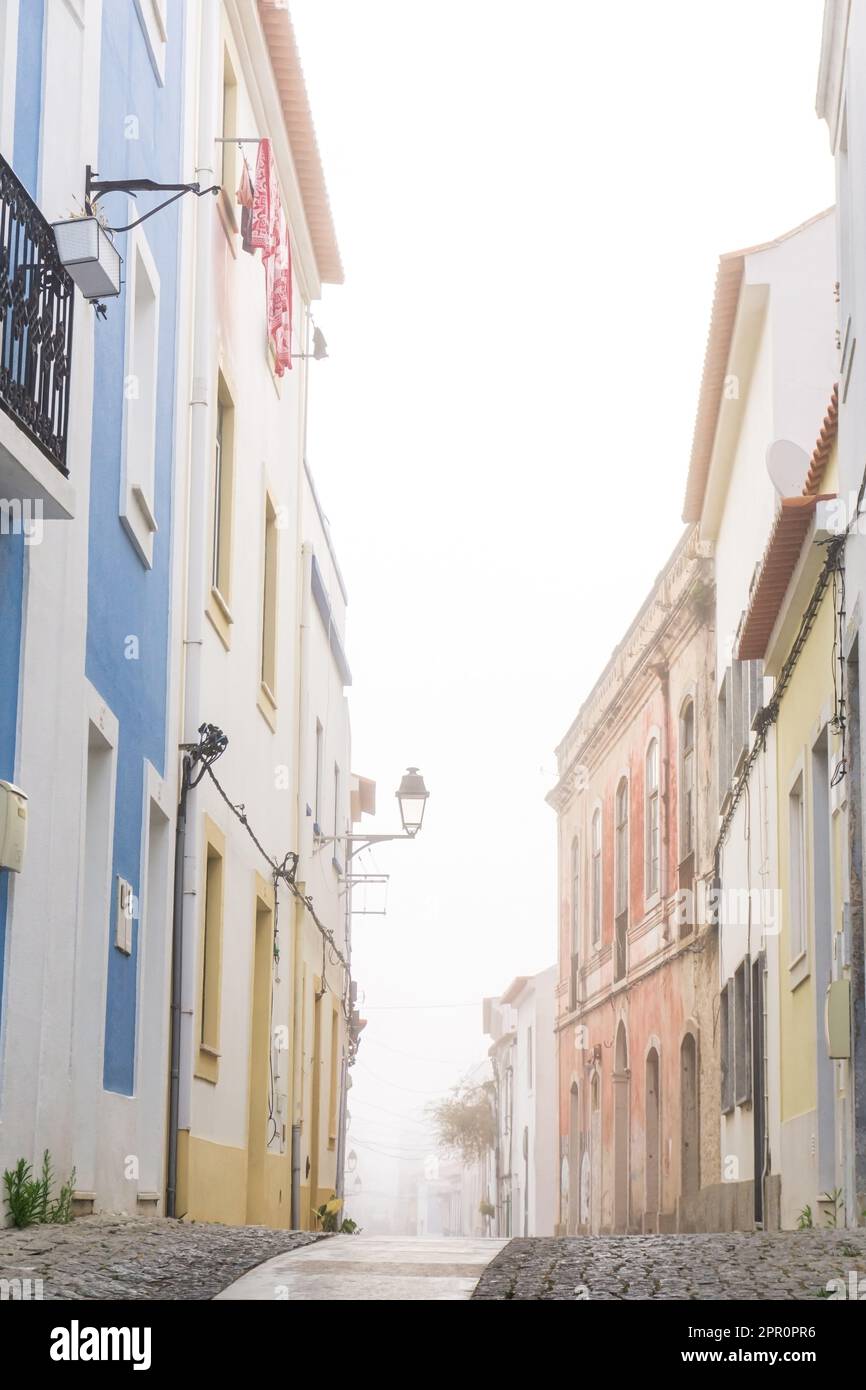 Street of a Portuguese town with colorful houses and paved road at dawn ...