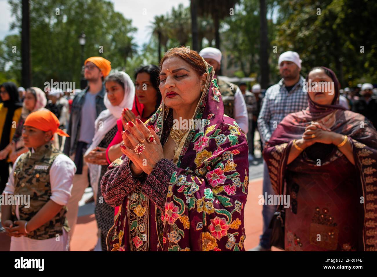A Sikh woman in traditional clothing prays during the procession for ...