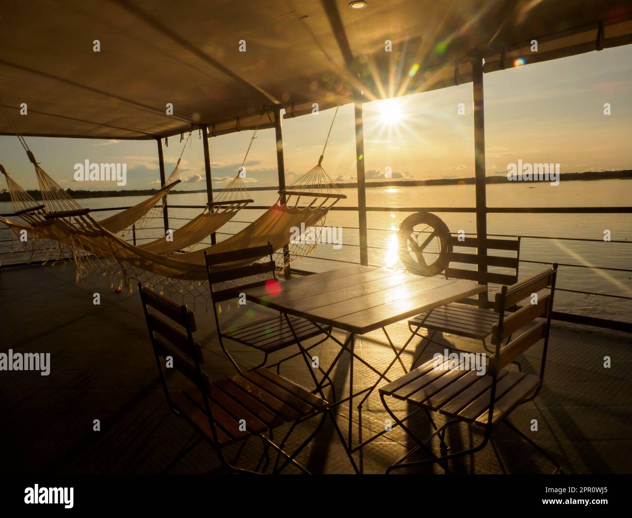 Sunset and hammocks on board a luxury tourist ship sailing the Amazon ...
