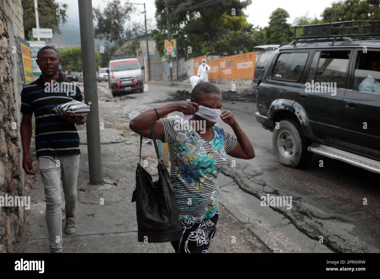 A woman walks past local authorities removing the bodies of men that ...