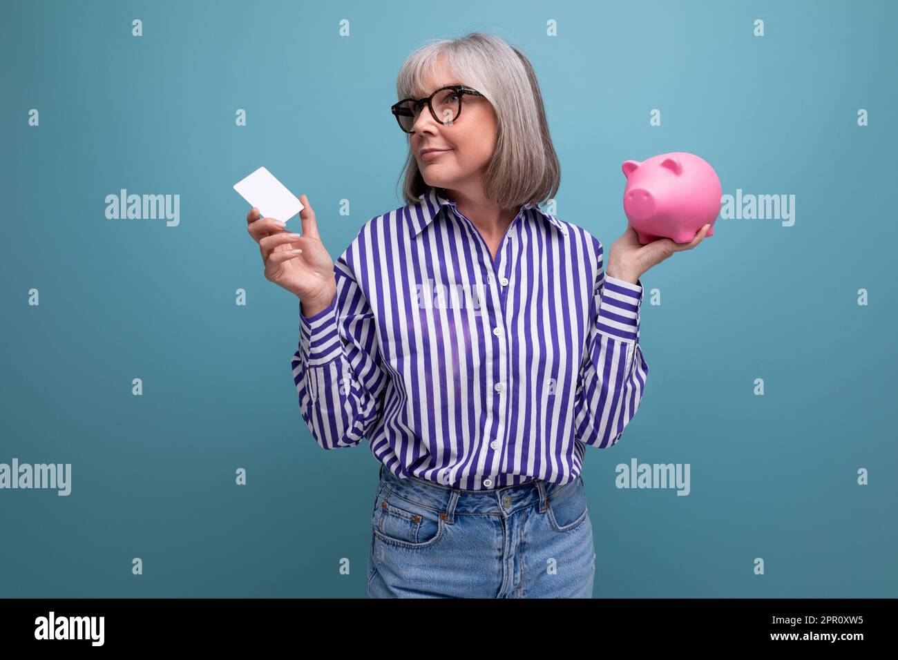 pension contribution. middle-aged woman with gray hair holding a piggy ...