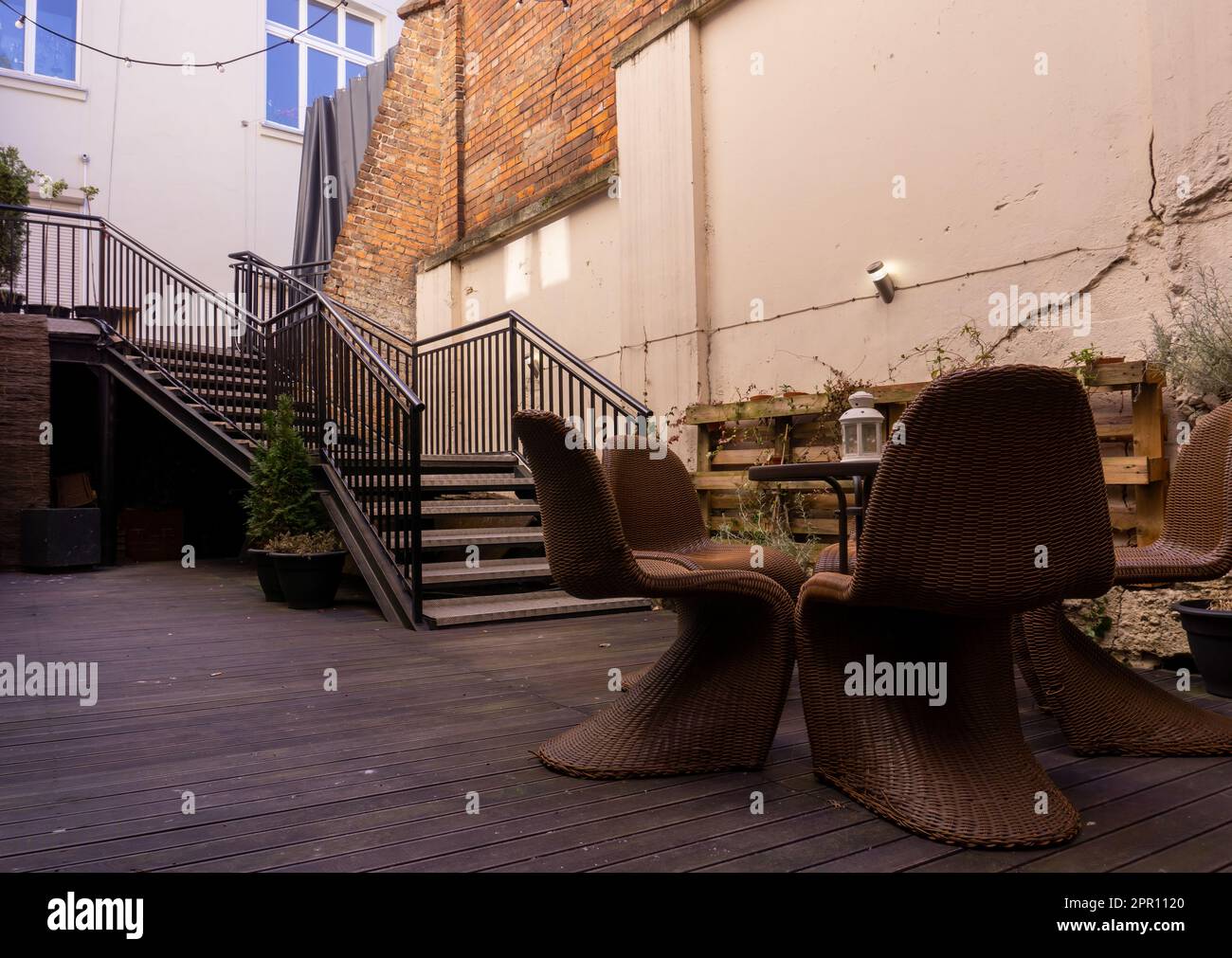 Cafe patio with brick walls, potted plants, stairs and wicker chairs ...
