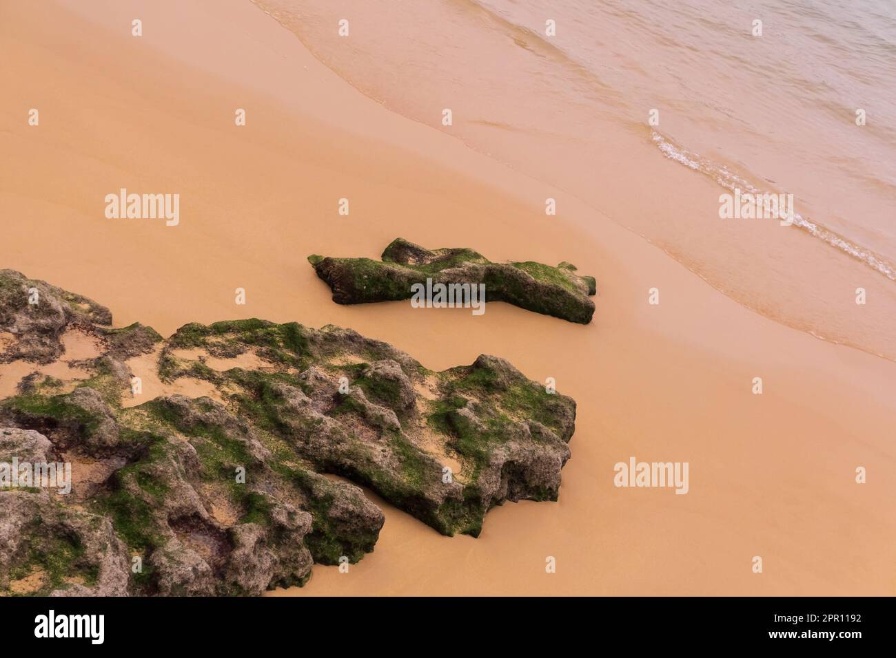 Waves roll on red sand and gray rocks close up Stock Photo - Alamy