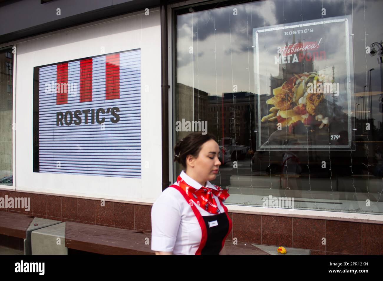 An employee of a new Rostic's restaurant walks by a Rostic's ad. The ...