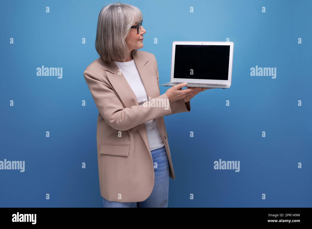 60s woman in jacket showing laptop screen mockup on bright background ...