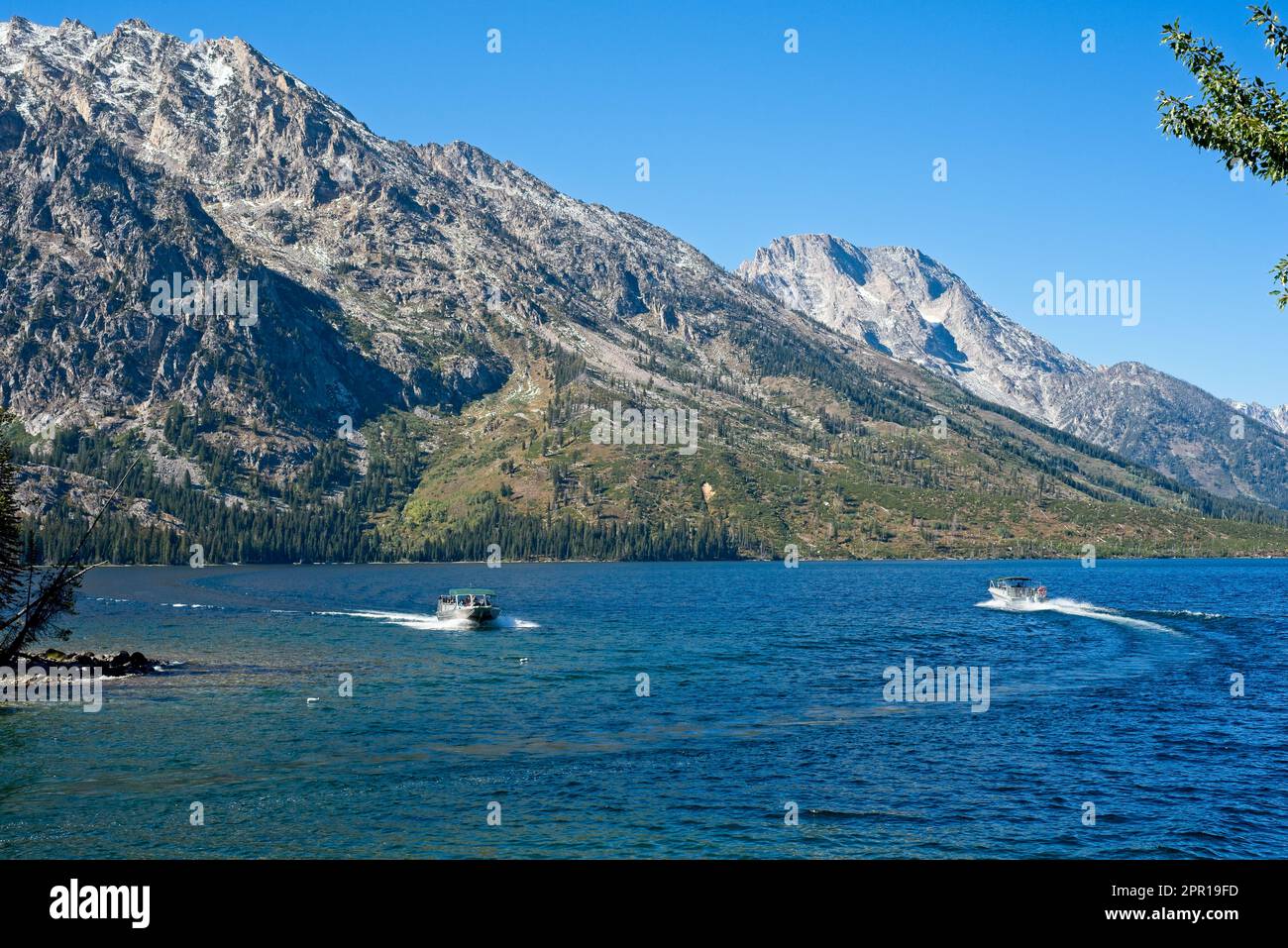 Shuttle boats on Jenny Lake in Grand Teton National Park pass each ...