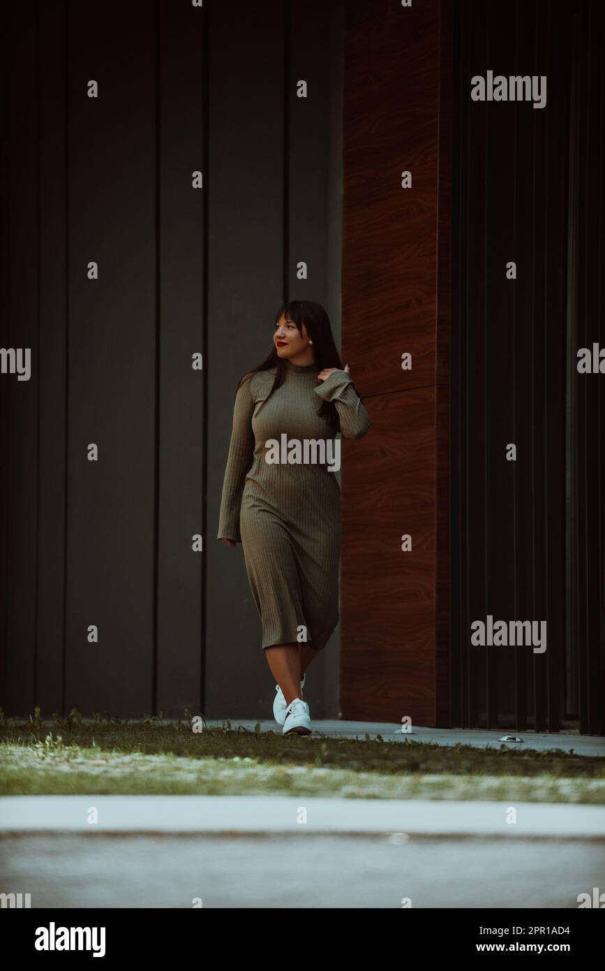 A confident and stylish plus-size woman walking by a modern building in ...