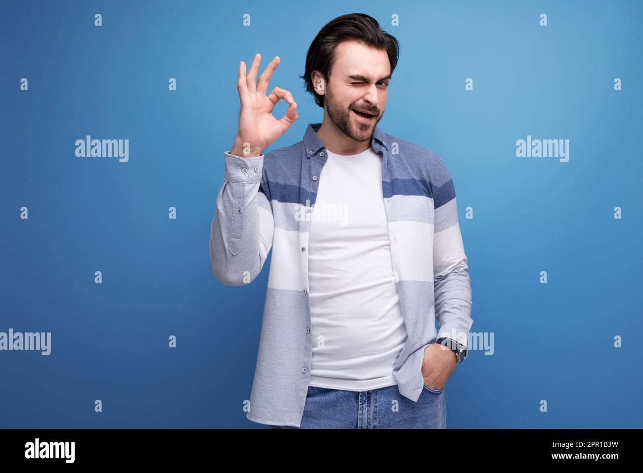 energetic young brunette man in model appearance on studio background ...