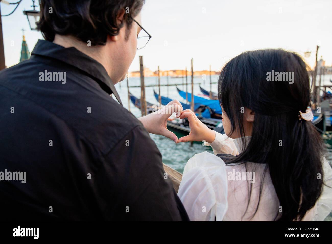Two lovers make a heart with their hands while on holiday in Venice in ...
