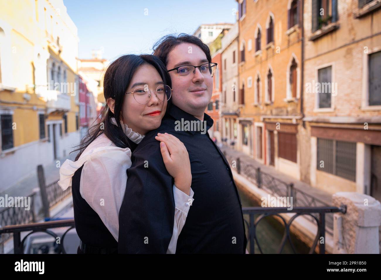 A mixed couple of lovers embrace while on vacation in Venice, the city ...