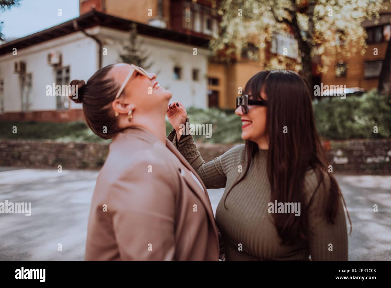 Two young women embrace each other emotionally outside on a sunny day ...