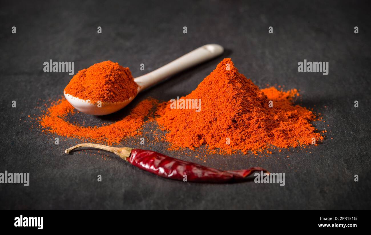 Red chili spices for recipes. A spoon and a pile of hot powder pepper ...
