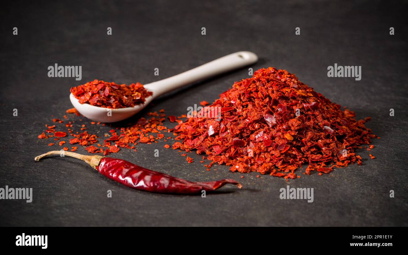 Red dried ground chili spices for recipes. A spoon and a pile of hot ...