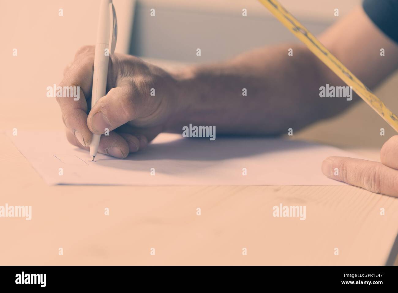 hand of a wood craftsman writing with a ballpoint pen on a paper ...