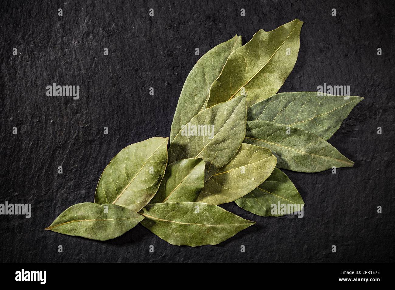 A bunch of dried bay leaves on a black background. Aromatic spices ...