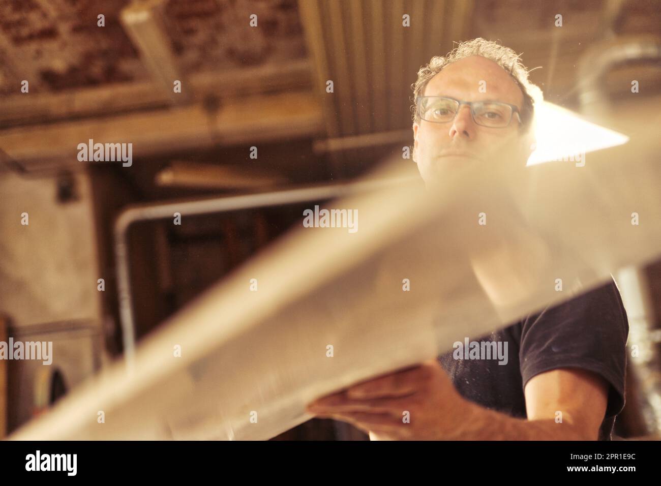 The carpenter is moving the wooden board. Man against the light with ...