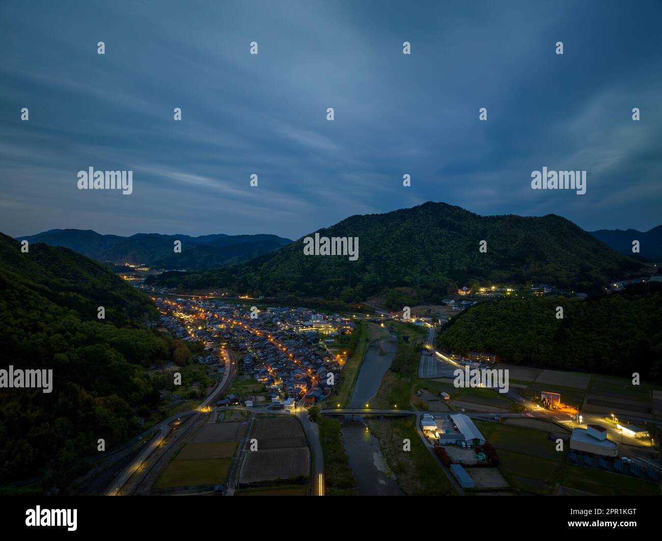 Aerial view of lights from small rural town between mountains at dusk ...