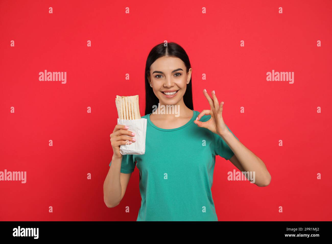 Happy young woman with delicious shawarma on red background Stock Photo ...