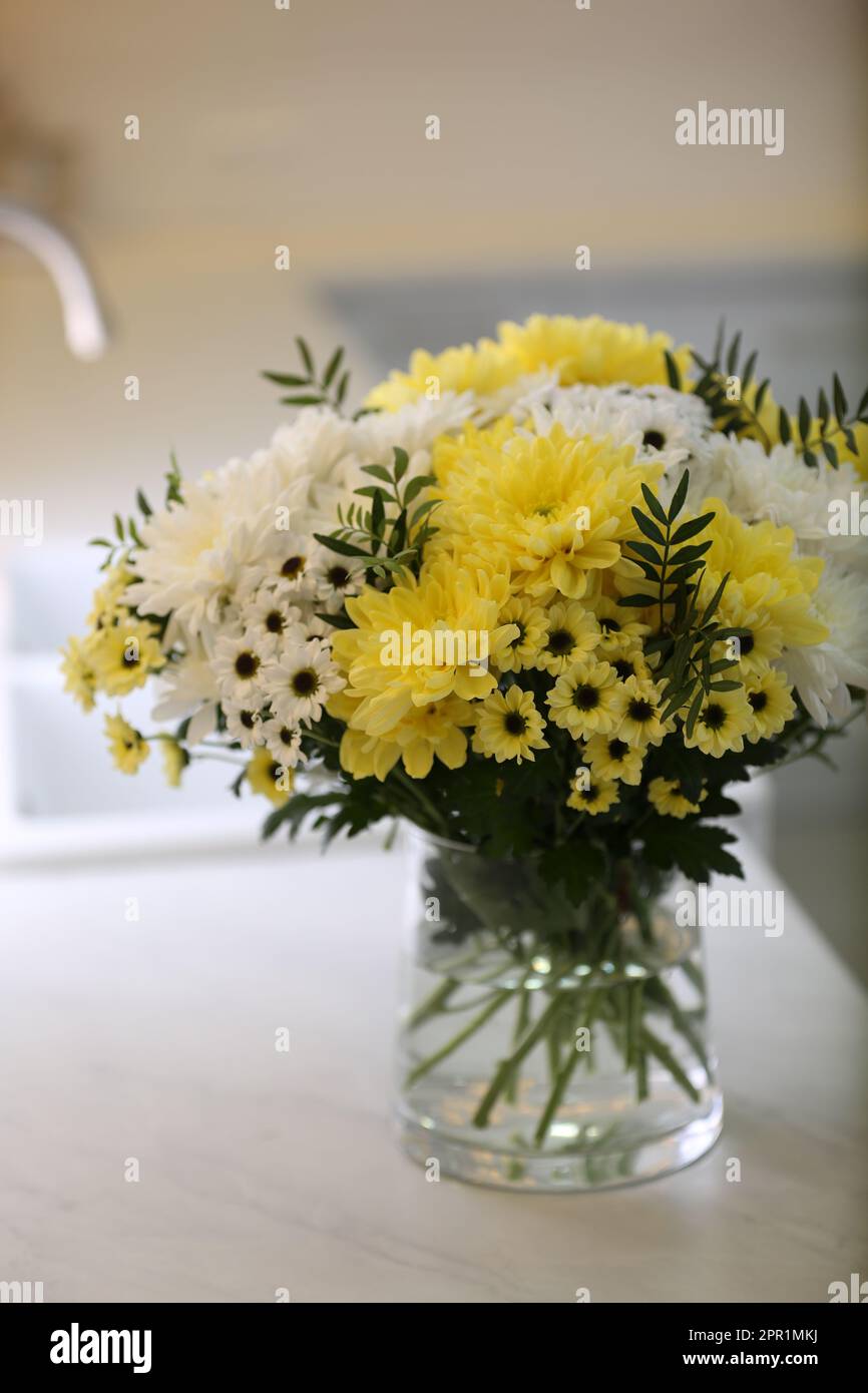 Vase with beautiful chrysanthemum flowers on countertop in kitchen ...
