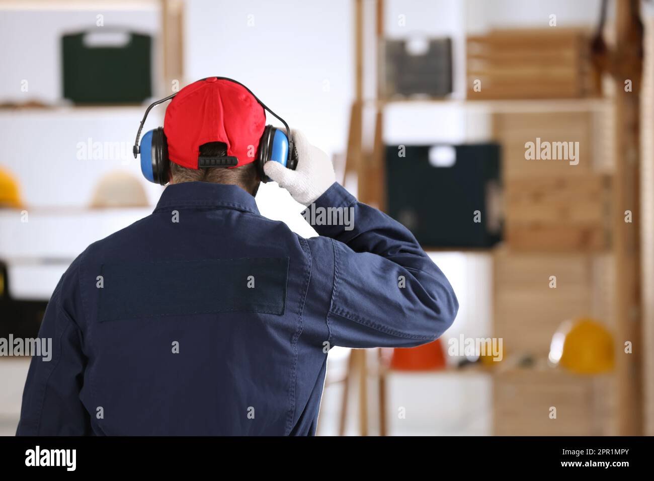 Worker wearing safety headphones indoors, back view. Hearing protection ...