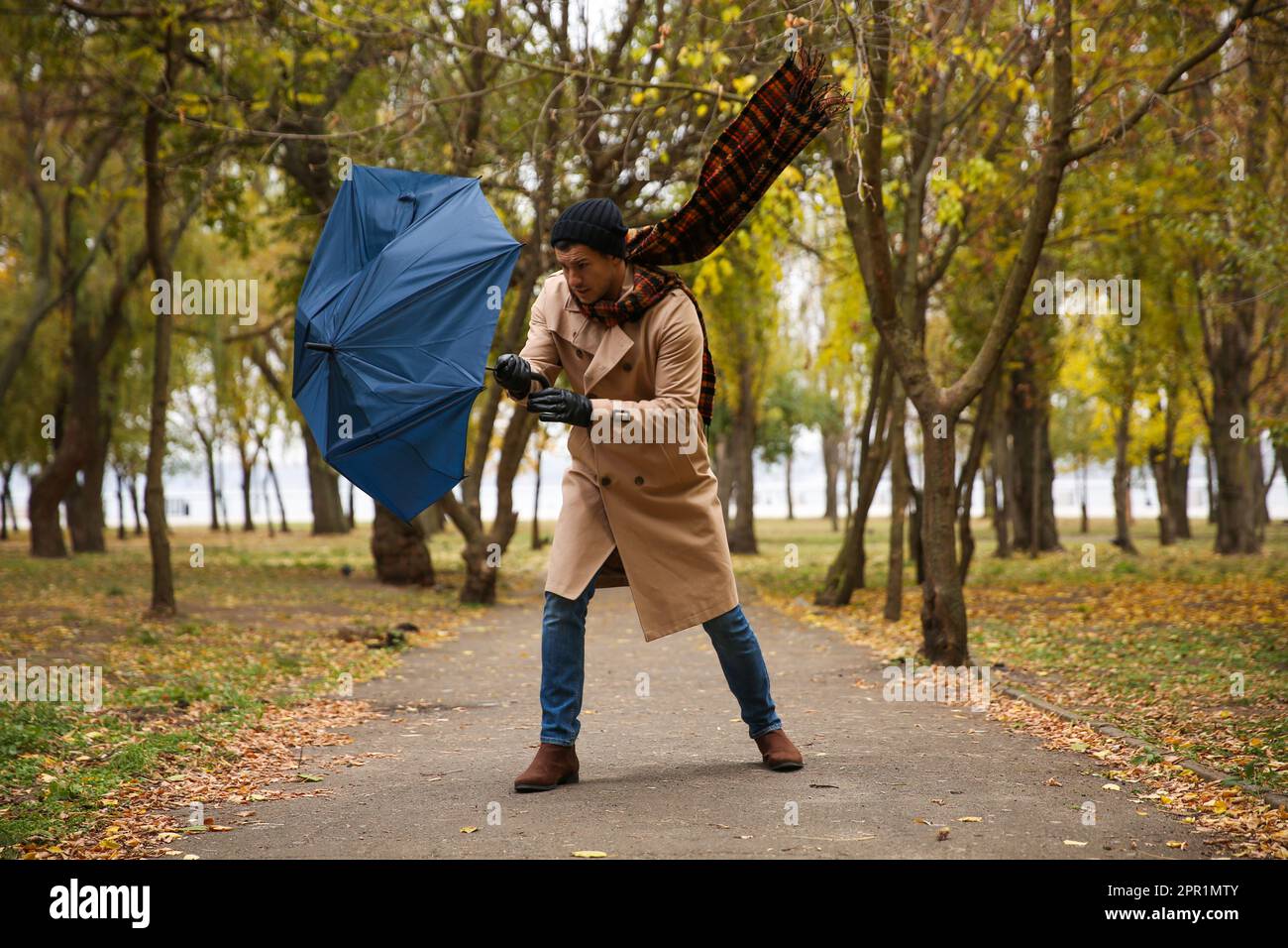 Man with blue umbrella caught in gust of wind outdoors Stock Photo - Alamy