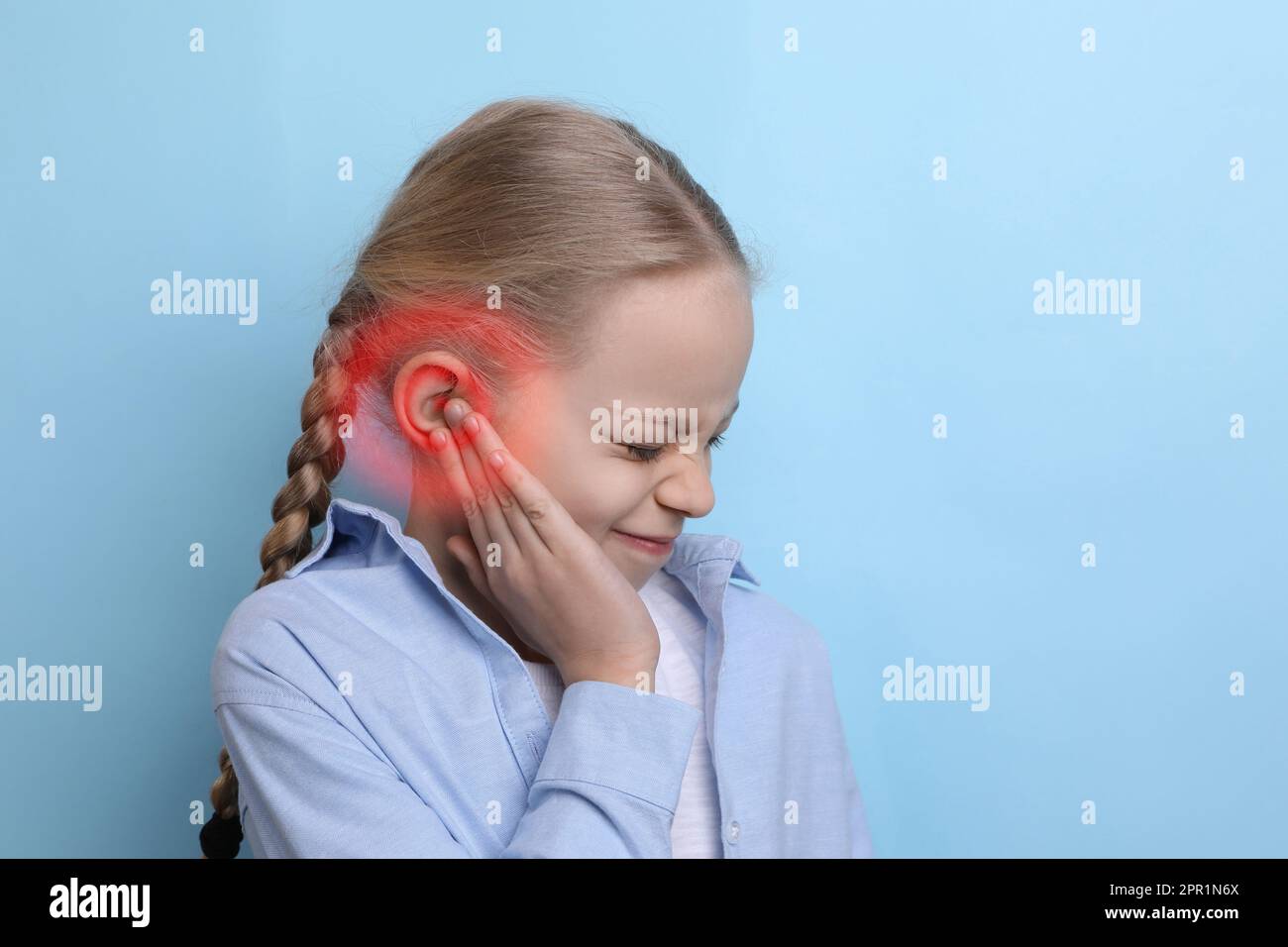 Little girl suffering from ear pain on light blue background, space for ...