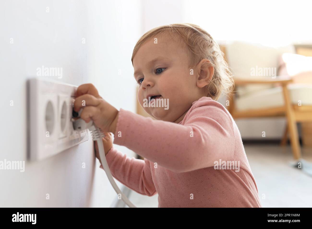 Cute baby playing with electrical socket and plug at home. Dangerous ...