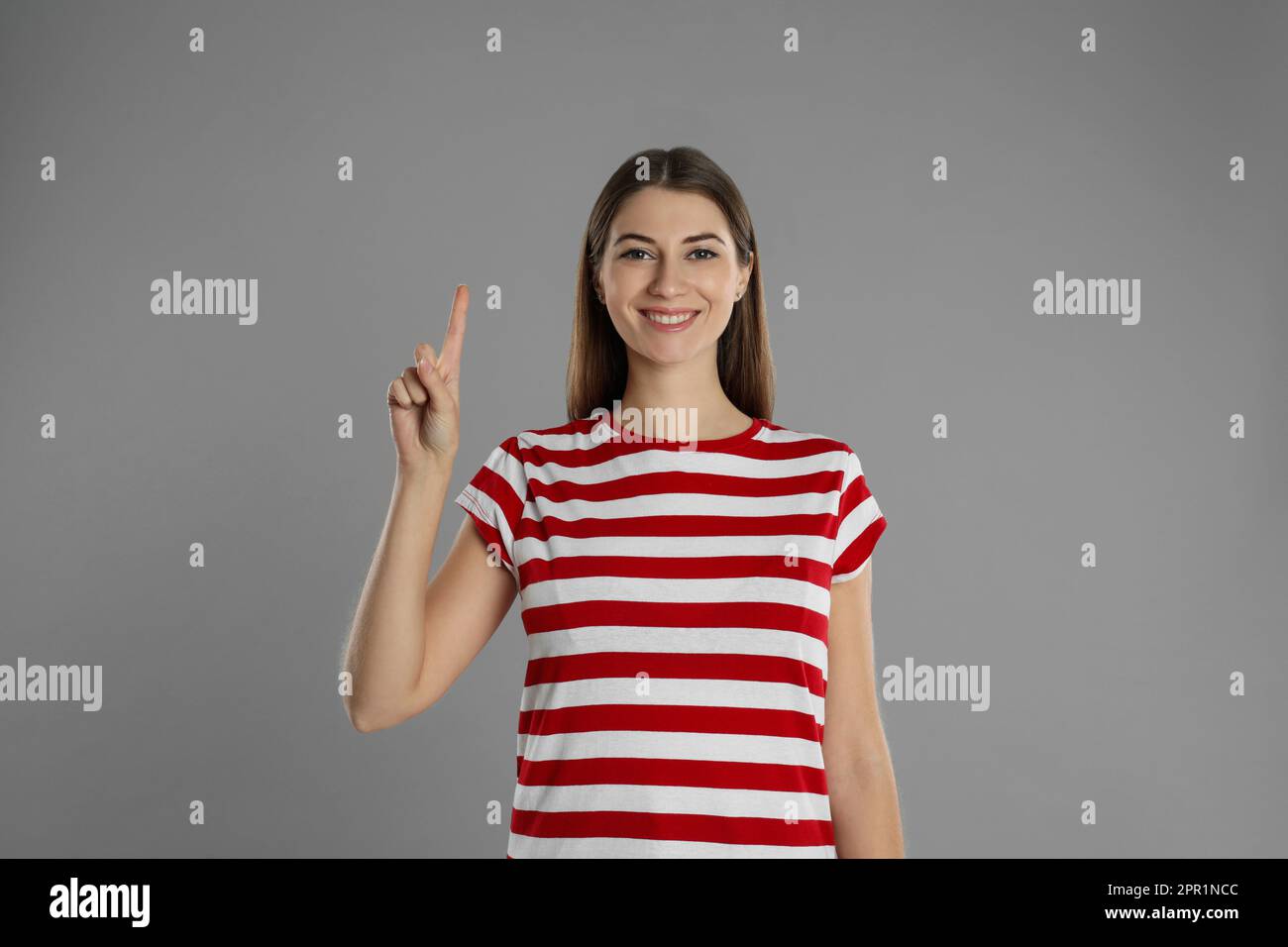 Woman showing number one with her hand on grey background Stock Photo ...