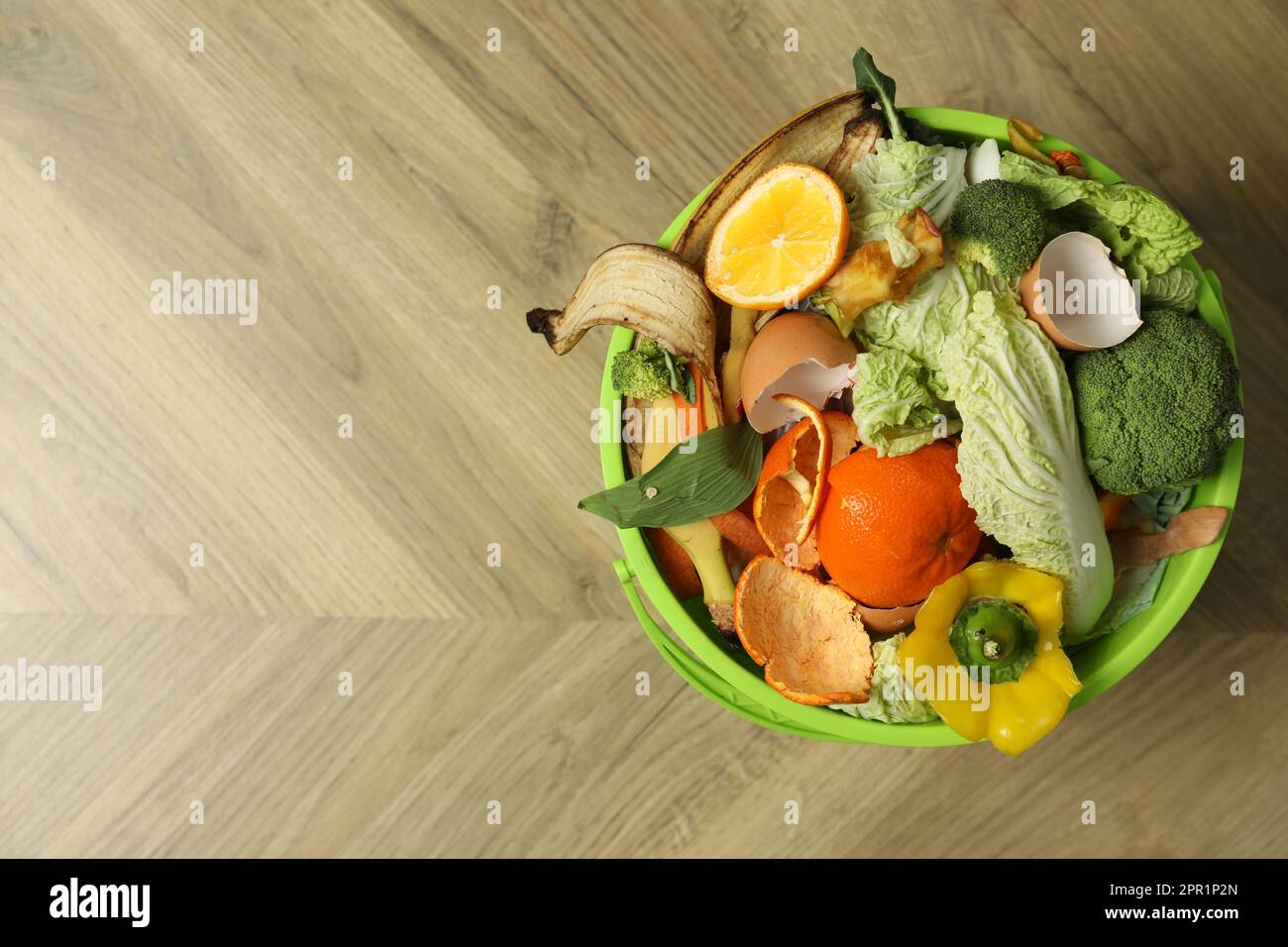Natural garbage in trash bin on wooden background, top view with space ...