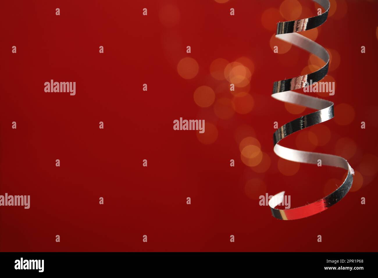 Shiny serpentine streamer against blurred lights. Space for text Stock ...