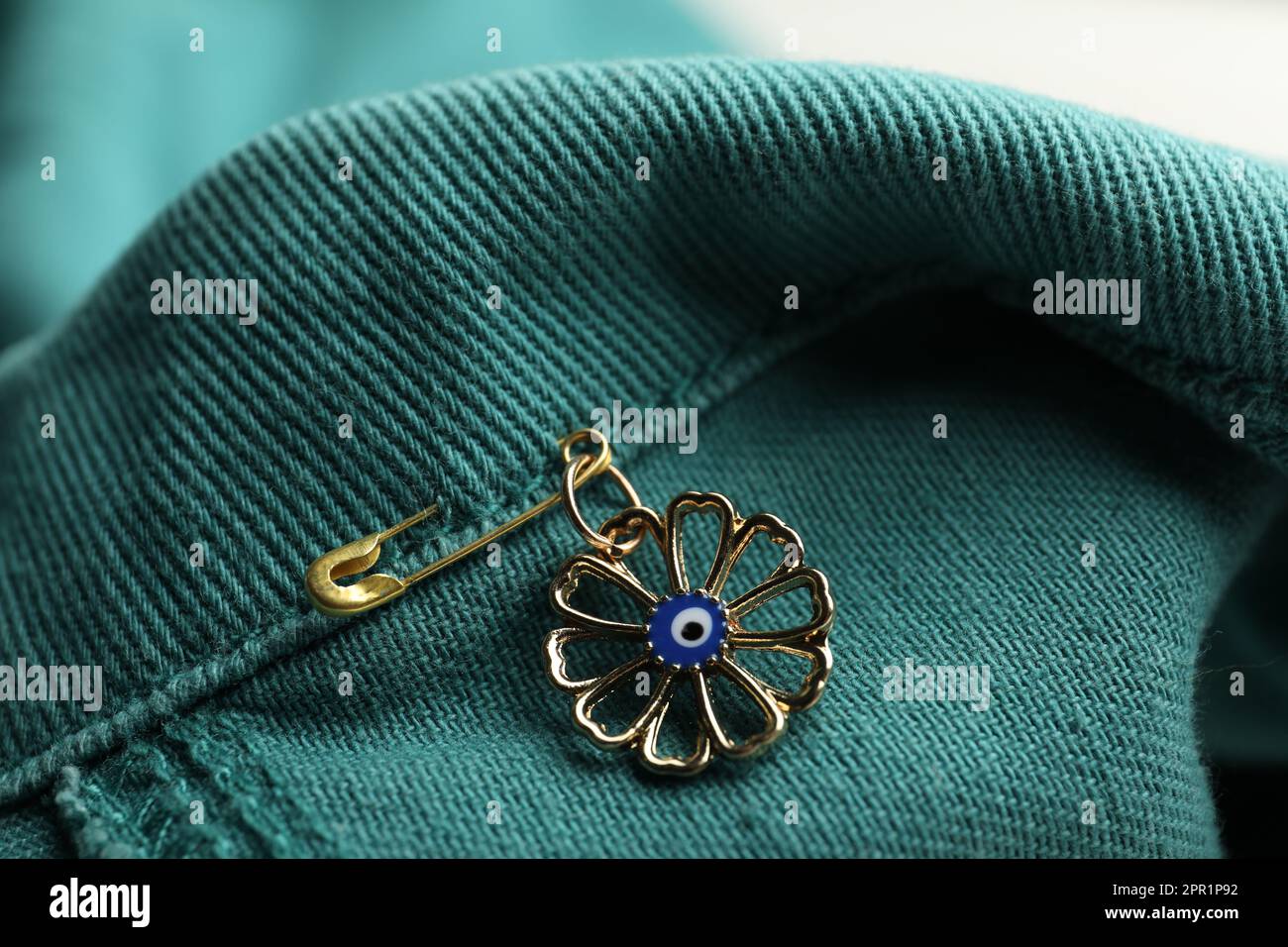 Evil eye safety pin on denim clothing, closeup Stock Photo - Alamy