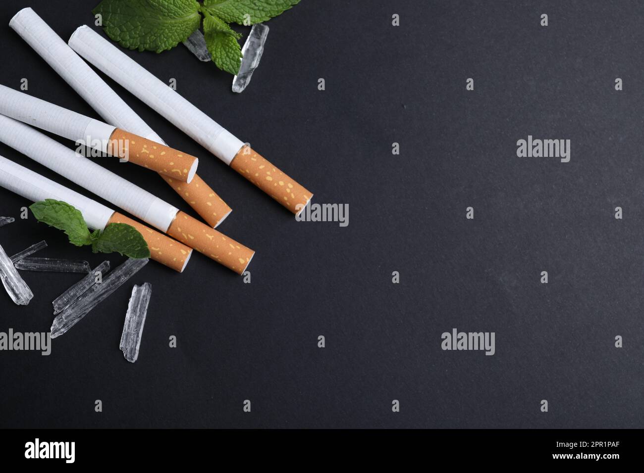 Cigarettes, menthol crystals and mint on black background, flat lay ...