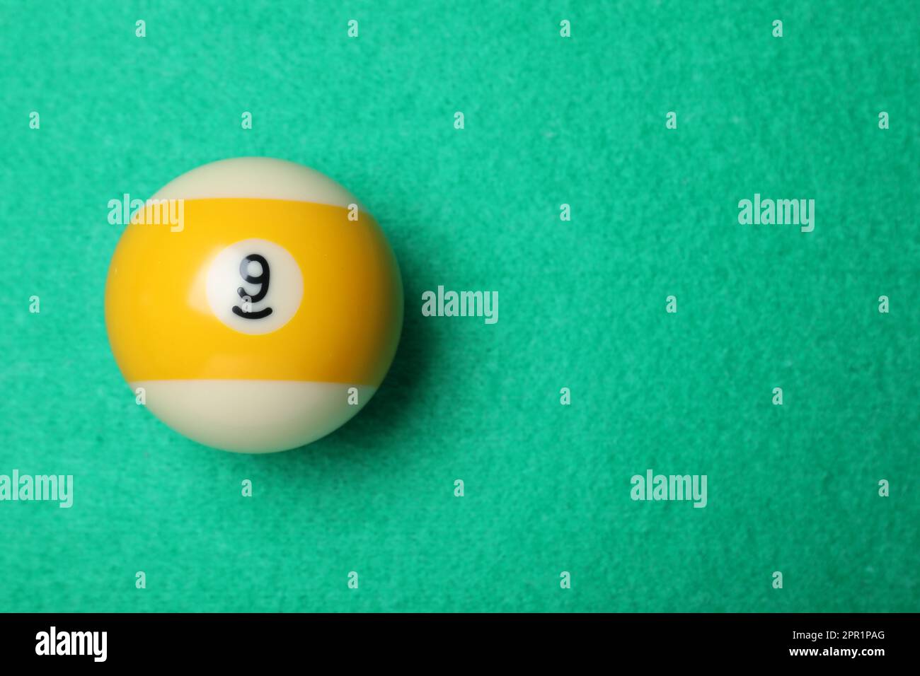 Billiard ball with number 9 on green table, top view. Space for text ...
