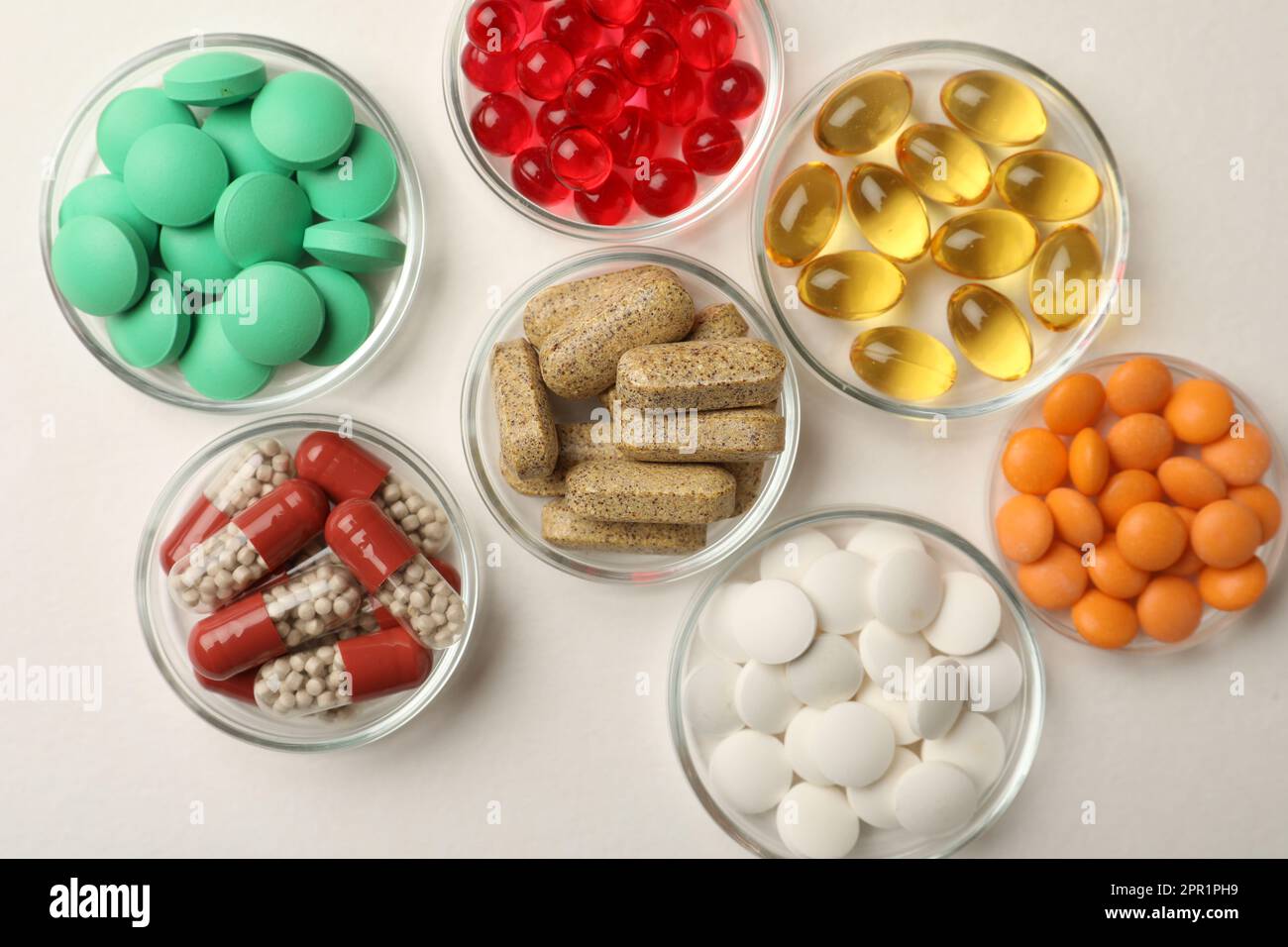 Different dietary supplements in bowls on white background, flat lay ...