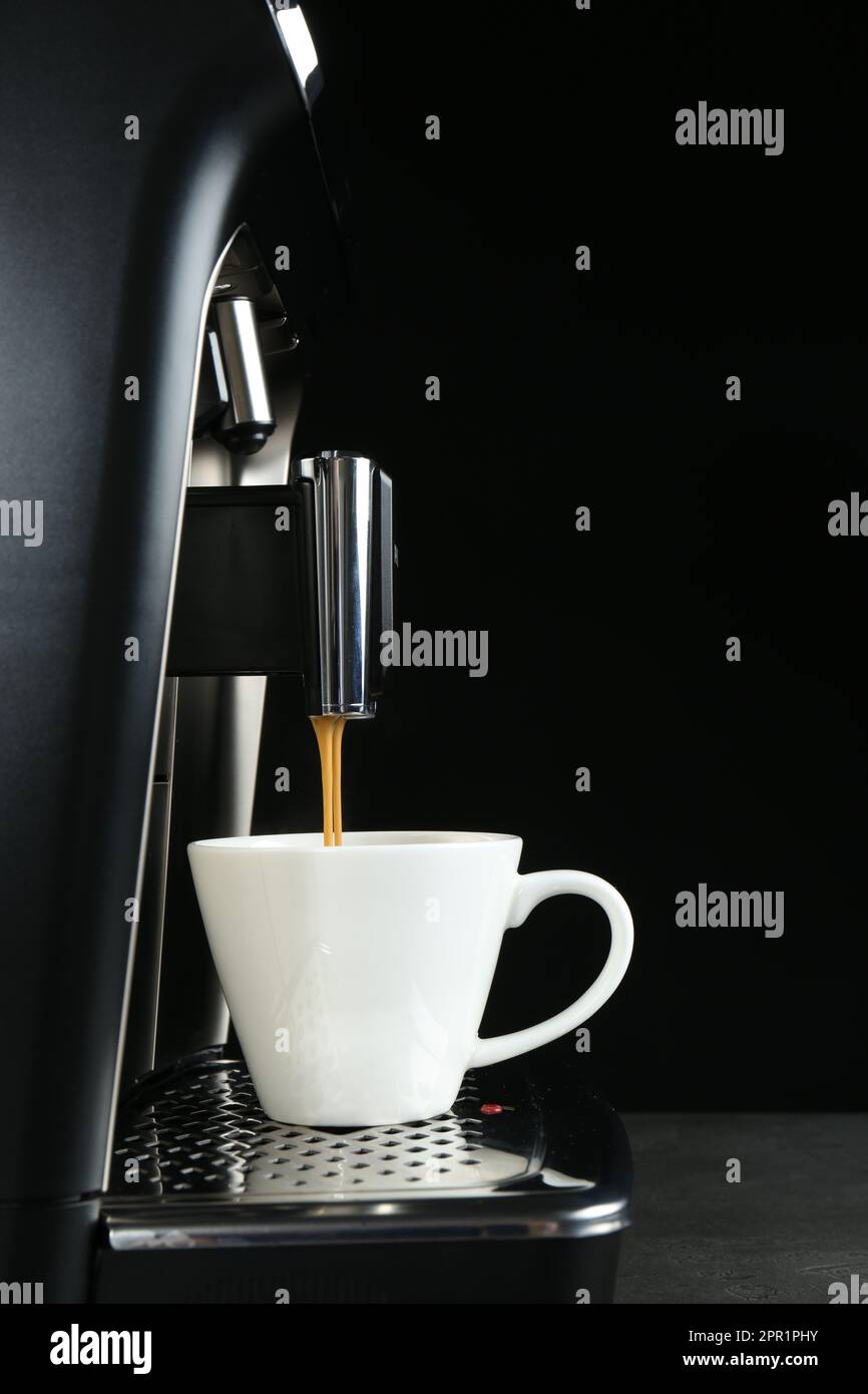 Modern espresso machine pouring coffee into cup on grey table against ...