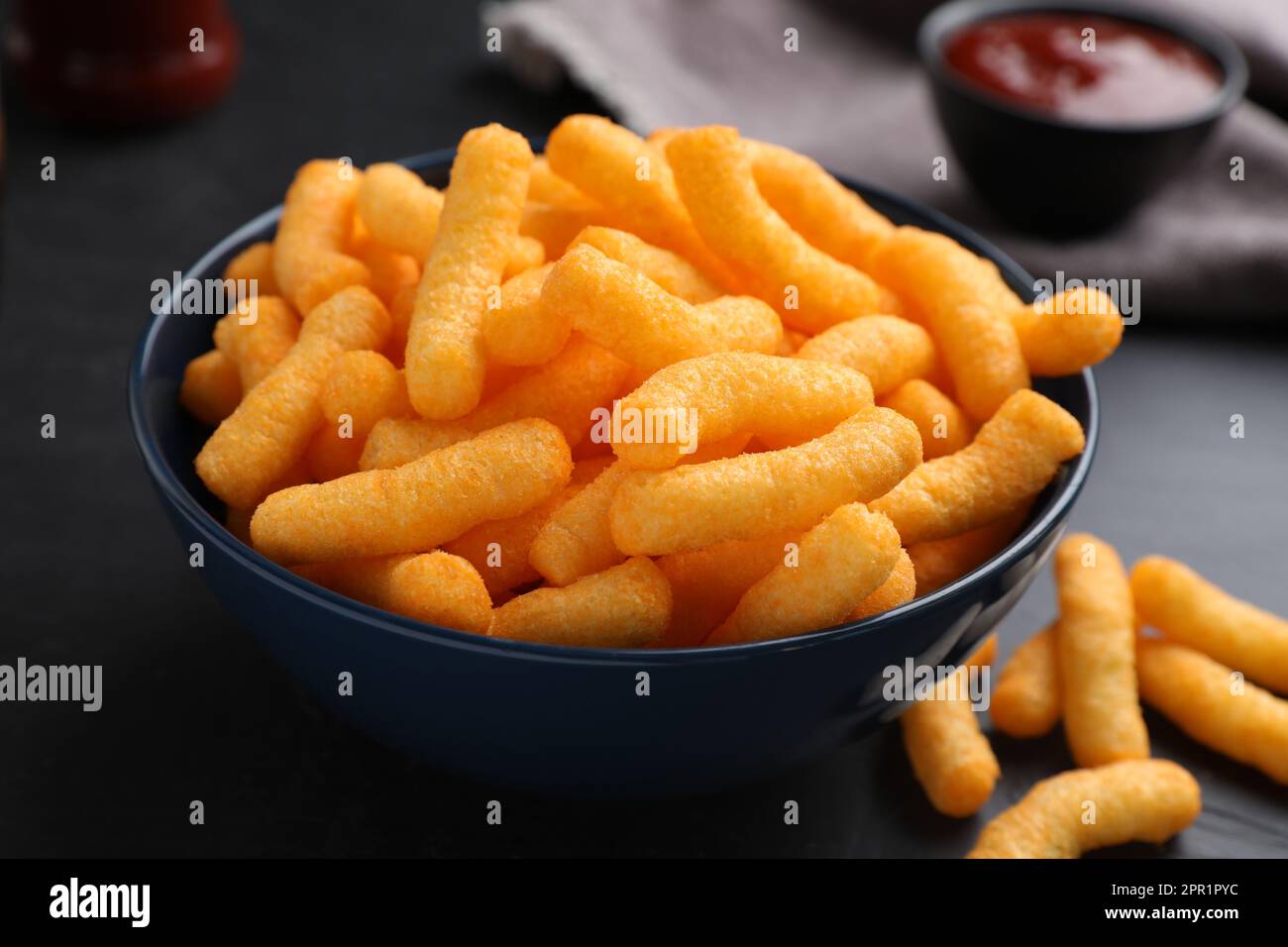 Bowl with crunchy cheesy corn snack on black table, closeup Stock Photo ...