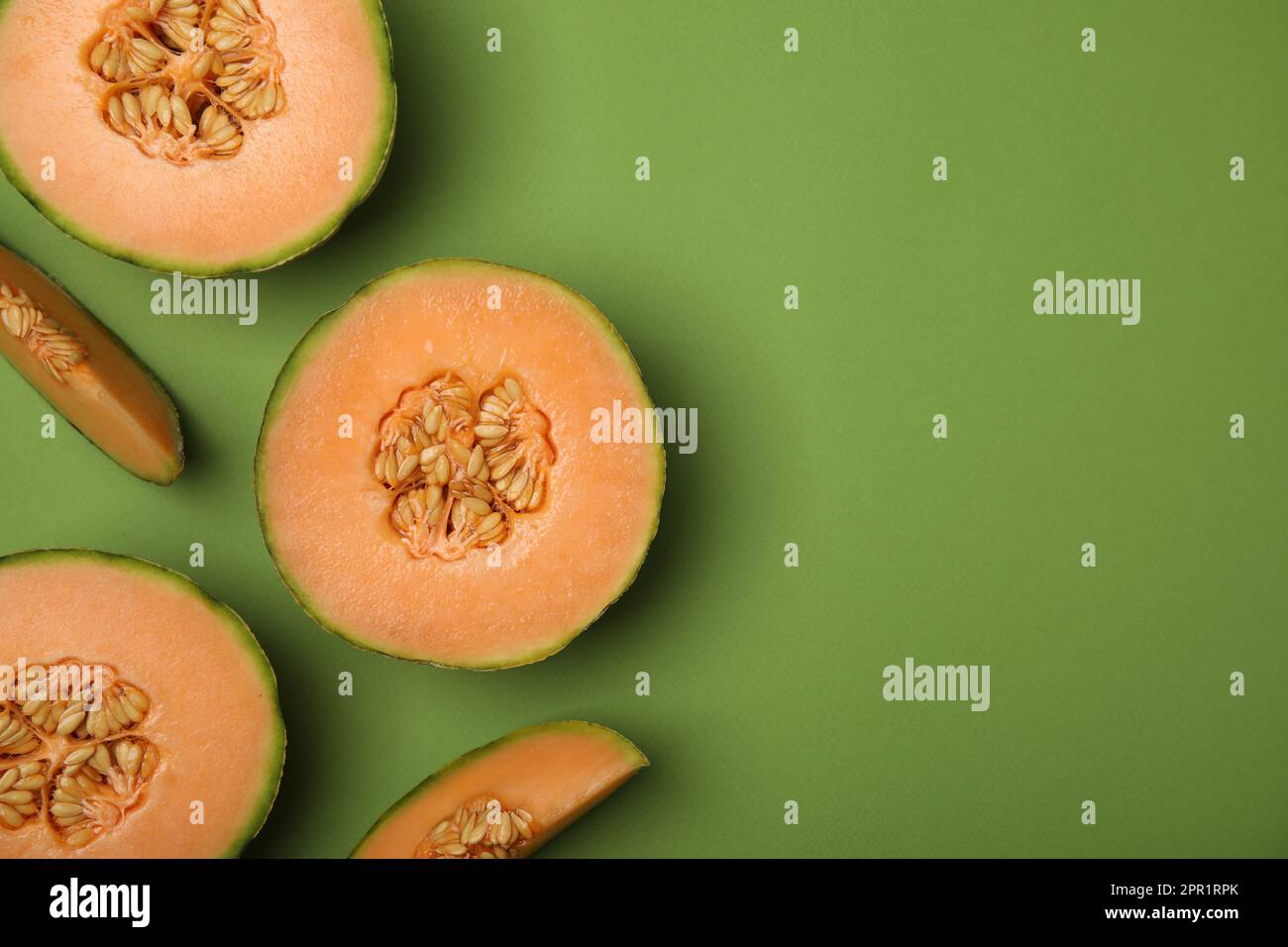 Cut melons on green background, flat lay. Space for text Stock Photo ...