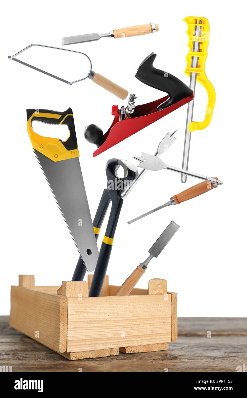 Different carpenter's tools falling into wooden box on white background ...